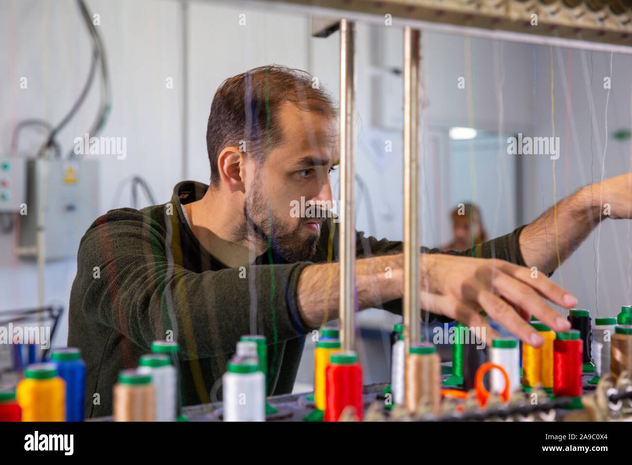 Worker at the textile factory that arranges the spools of yarn ...