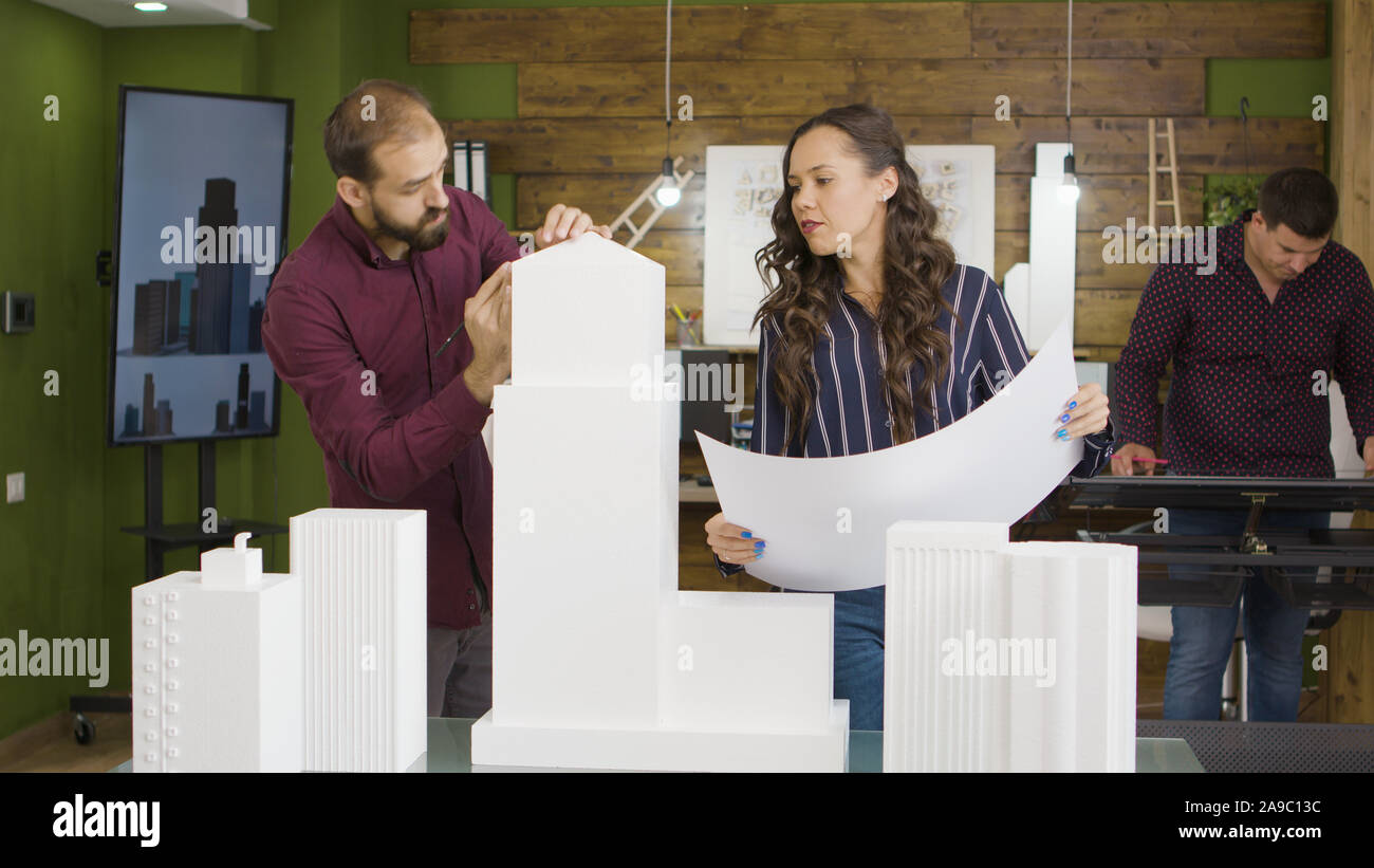 Group of architects working on 3D printed models of buildings ...