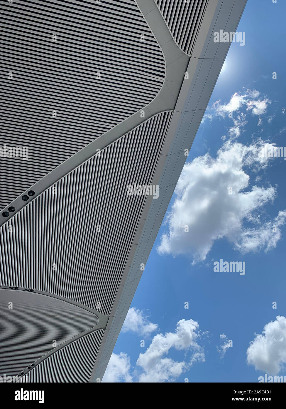 Bottom view of modern architectural ceiling and cloudy blue sky in the ...