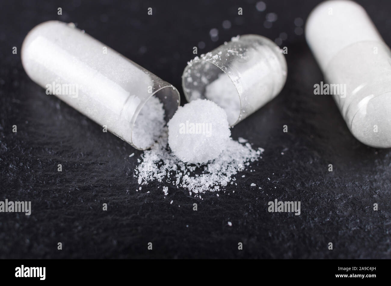 one open capsule of msm, sulfur, methyl sulfonyl methan on black ...