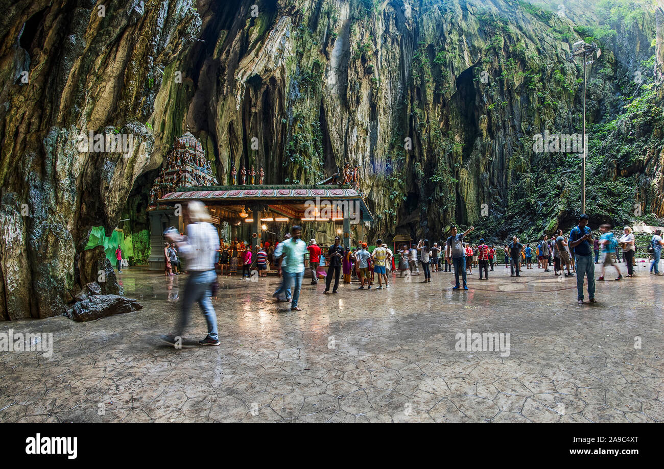 Tourist and local people walking inside Hindu cave temple which is made ...