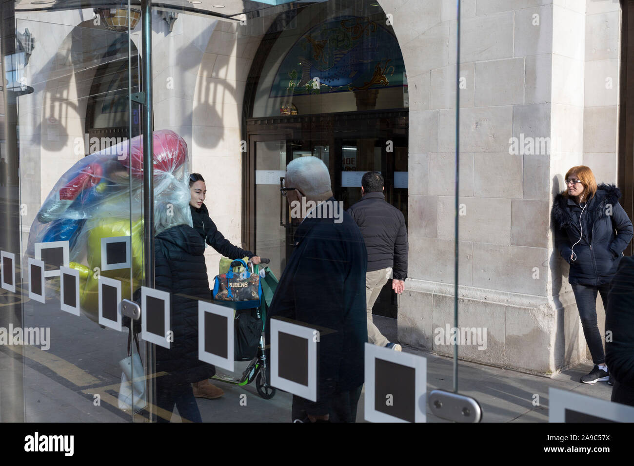 A lady pushes a child's buggy while carrying inflated party balloons ...