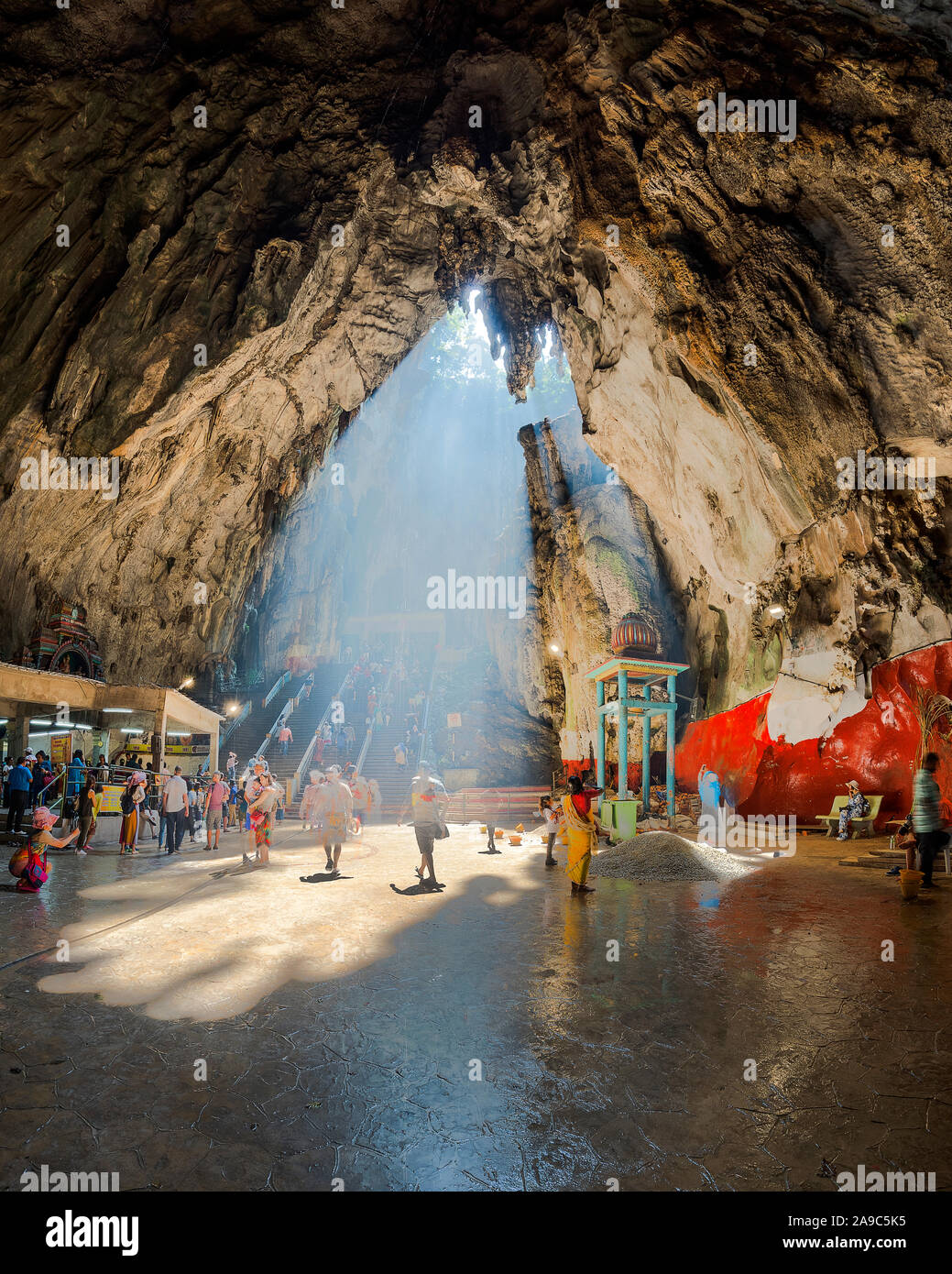 Tourist and local people walking inside Hindu cave temple which is made ...