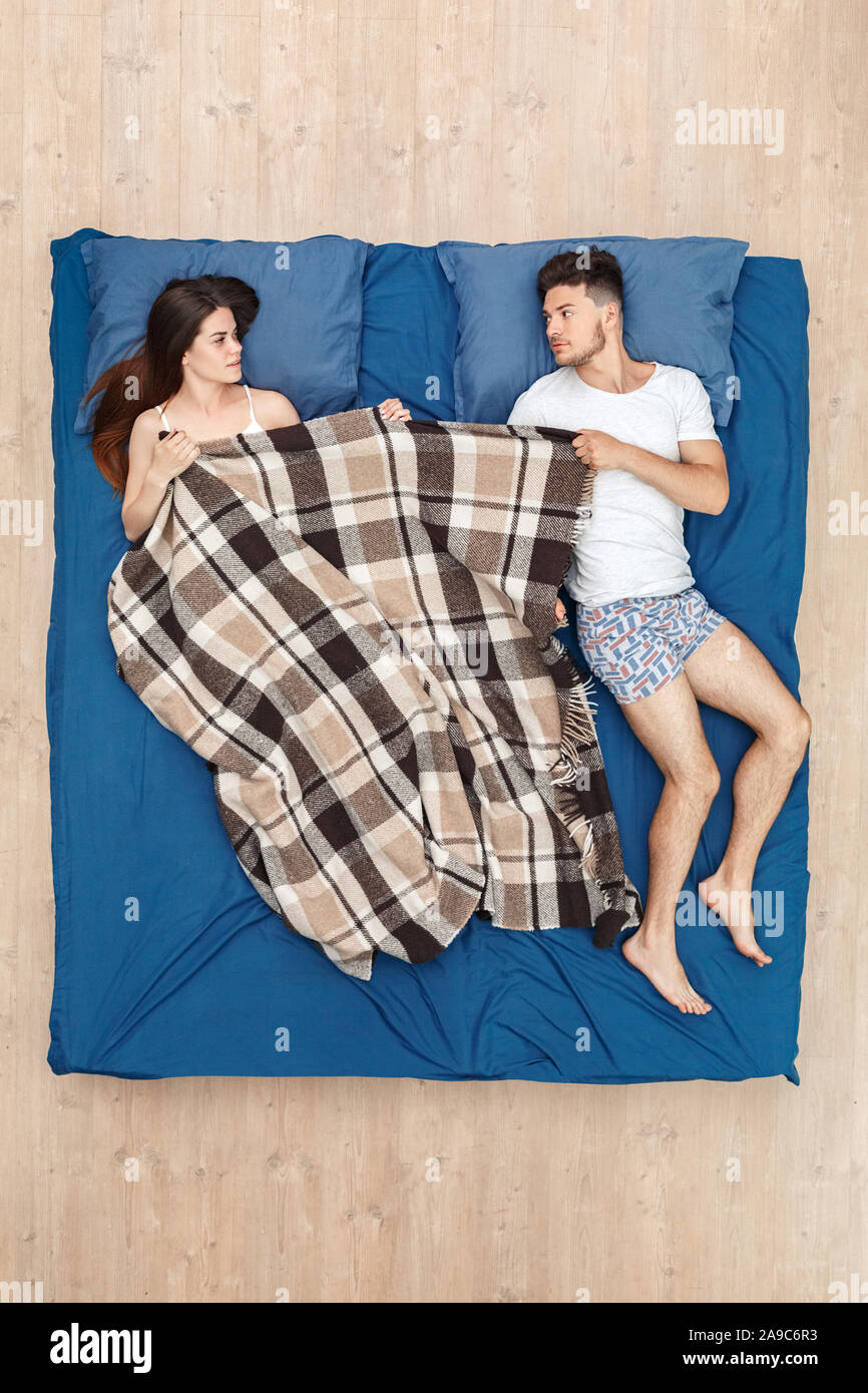 Bedtime. Young couple lying fighting fot blanket on bed top view ...