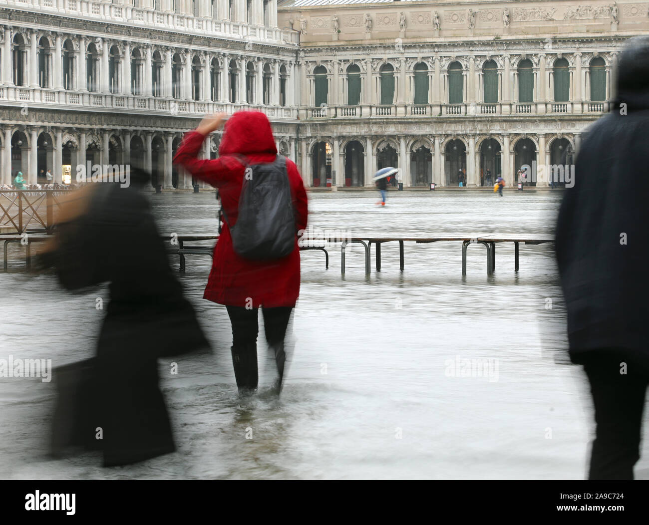woman with red rain coat in Saint Mark square in Venice Italy whitel ...