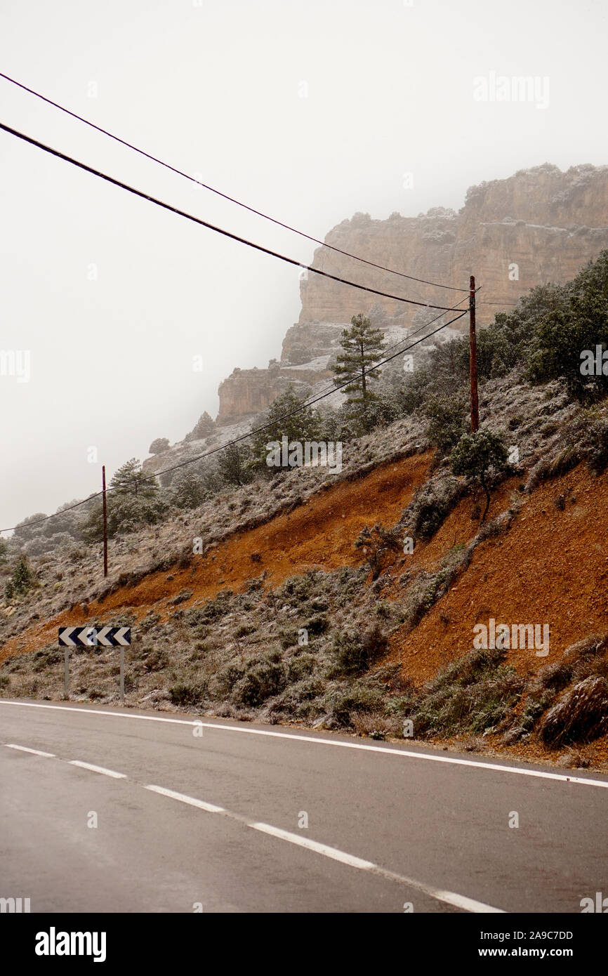 An unusual dusting of snow on a Spanish red rocky arid roadside scenery ...
