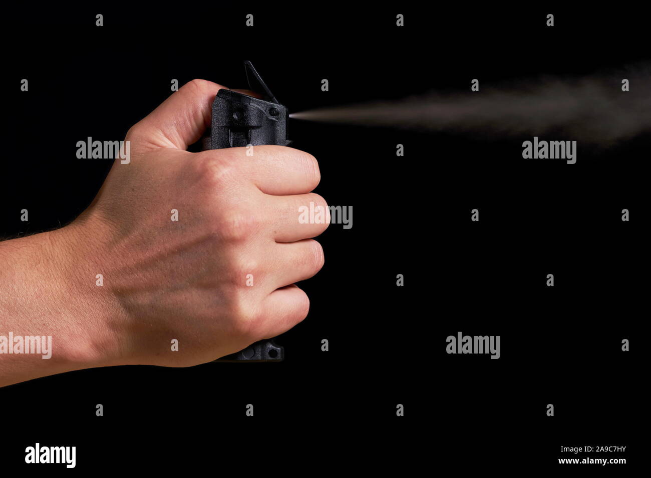 man aiming and spraying pepper spray with visible fog on black ...