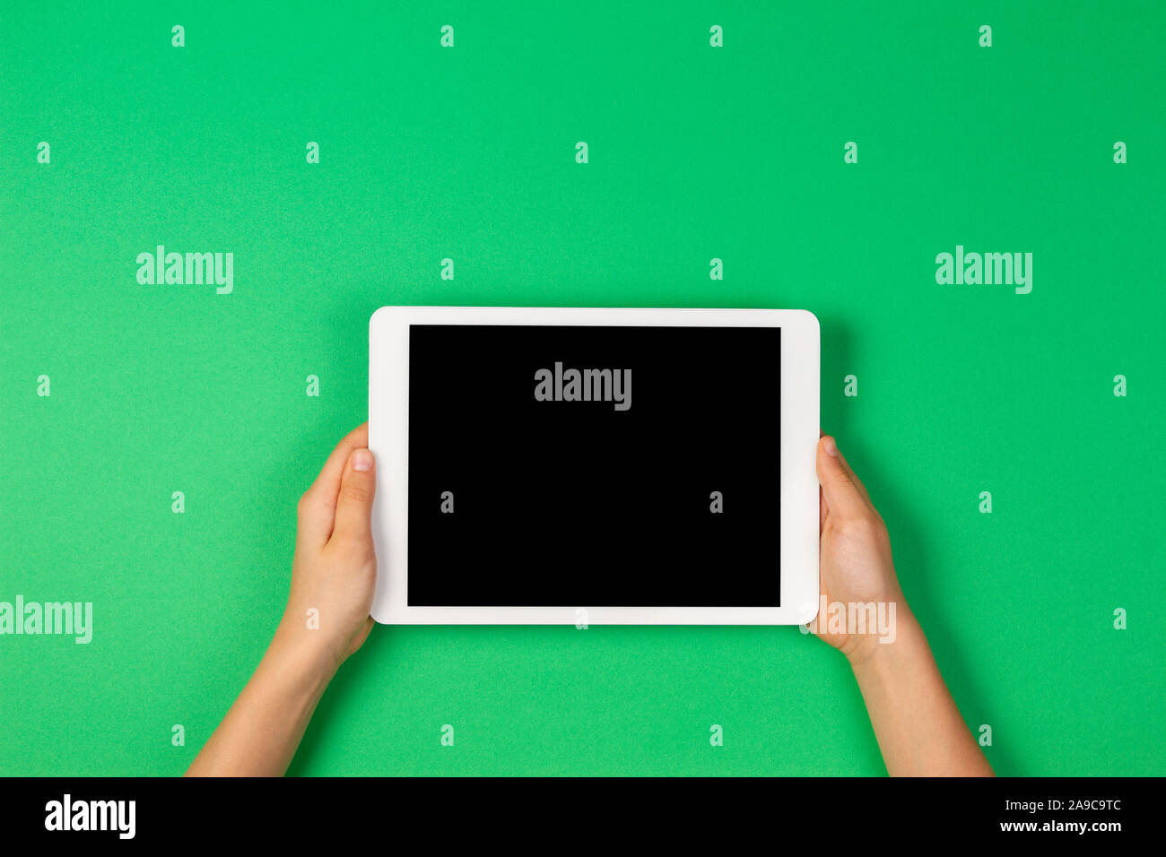 Child hands holding tablet computer on light green background Stock ...