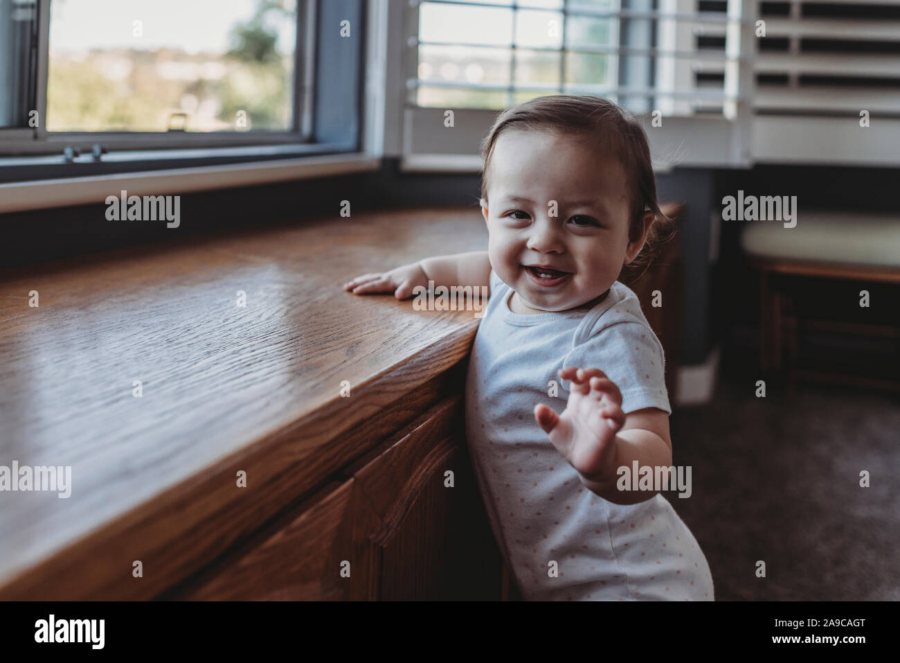Happy smiling baby with two teeth standing by window Stock Photo - Alamy