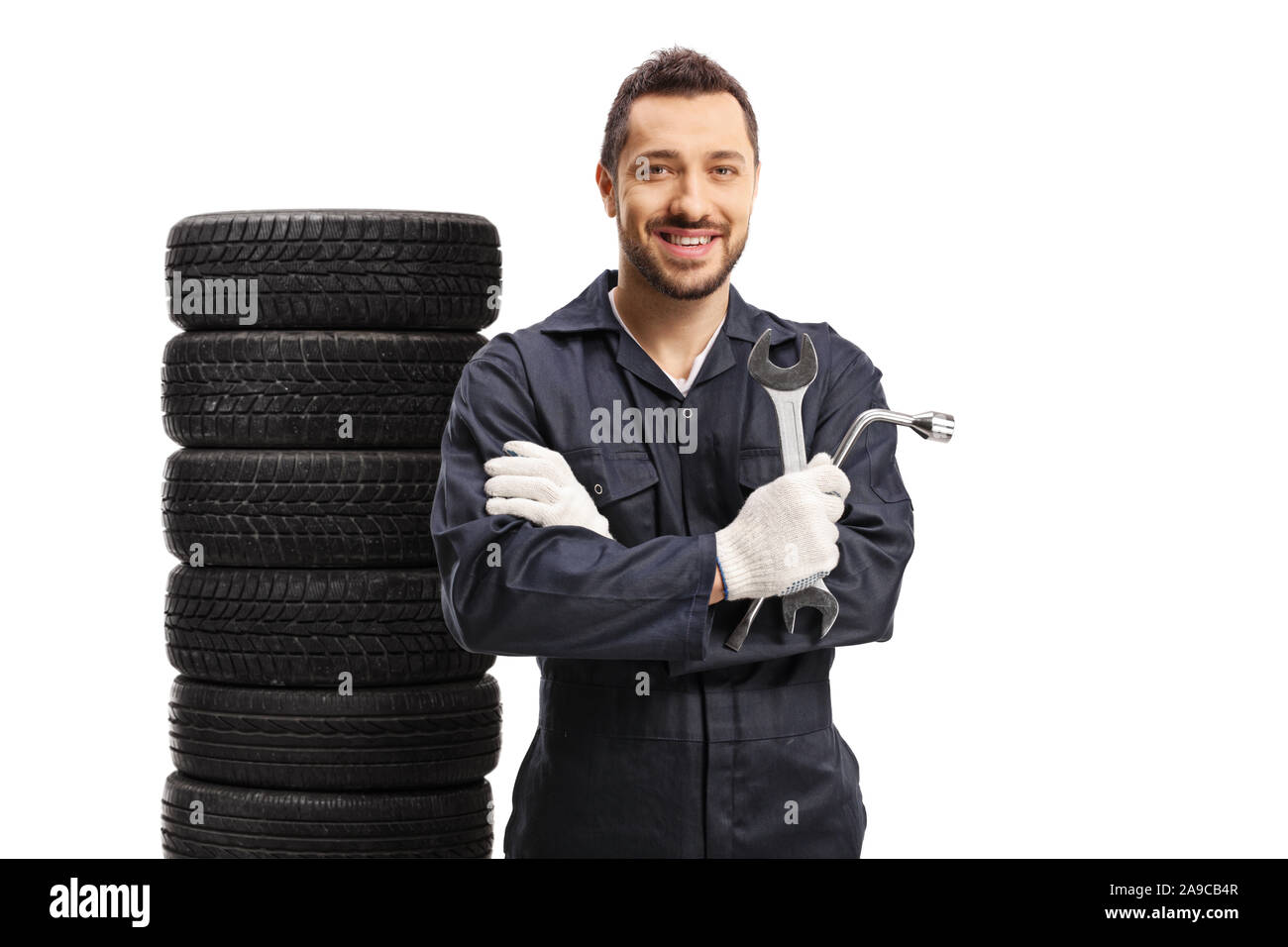 Auto mechanic holding car repair equipment and posing with a pile of ...