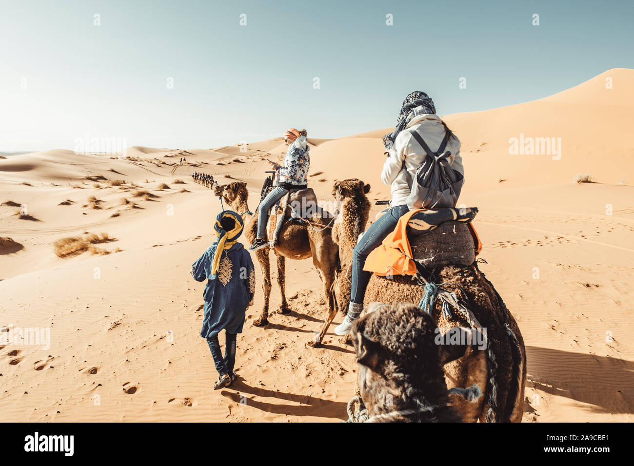 people riding dromedary through the desert Stock Photo - Alamy