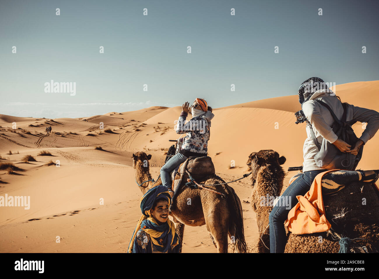 people riding dromedary through the desert Stock Photo - Alamy