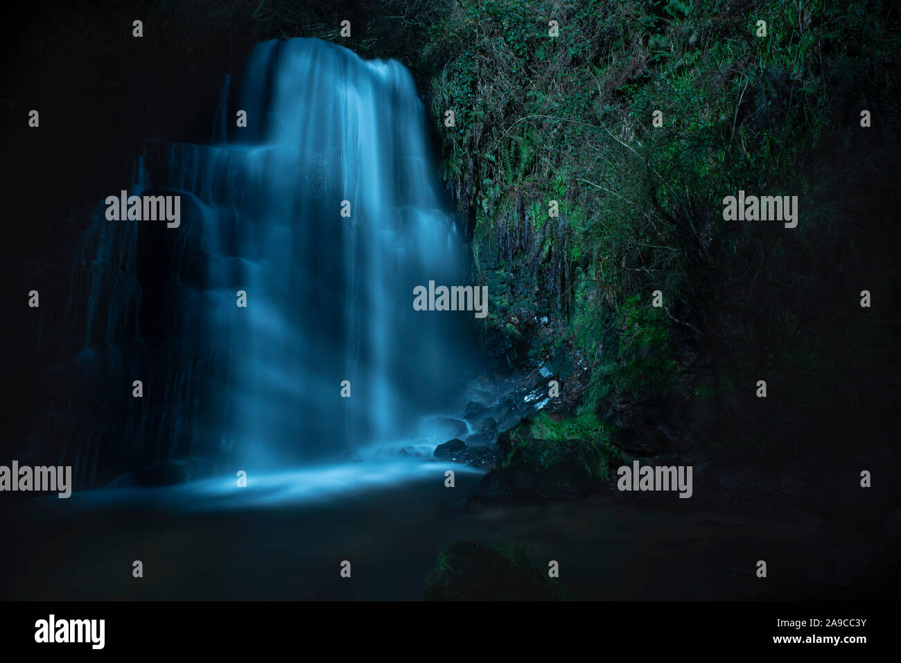 long exposure of secluded waterfall, silky smooth water flowing down ...