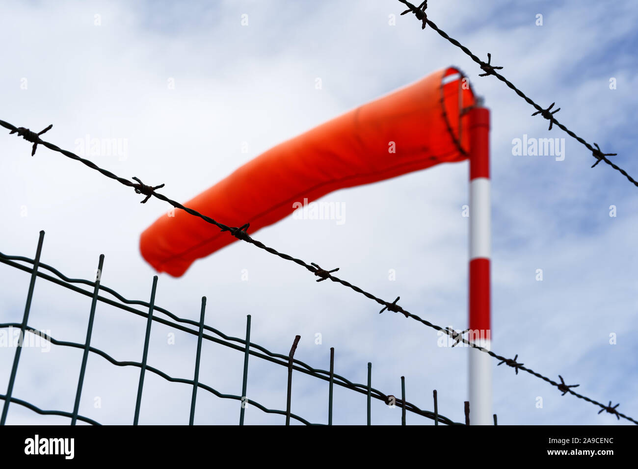 View from below of a bright red bulging windsock of an airfield behind ...