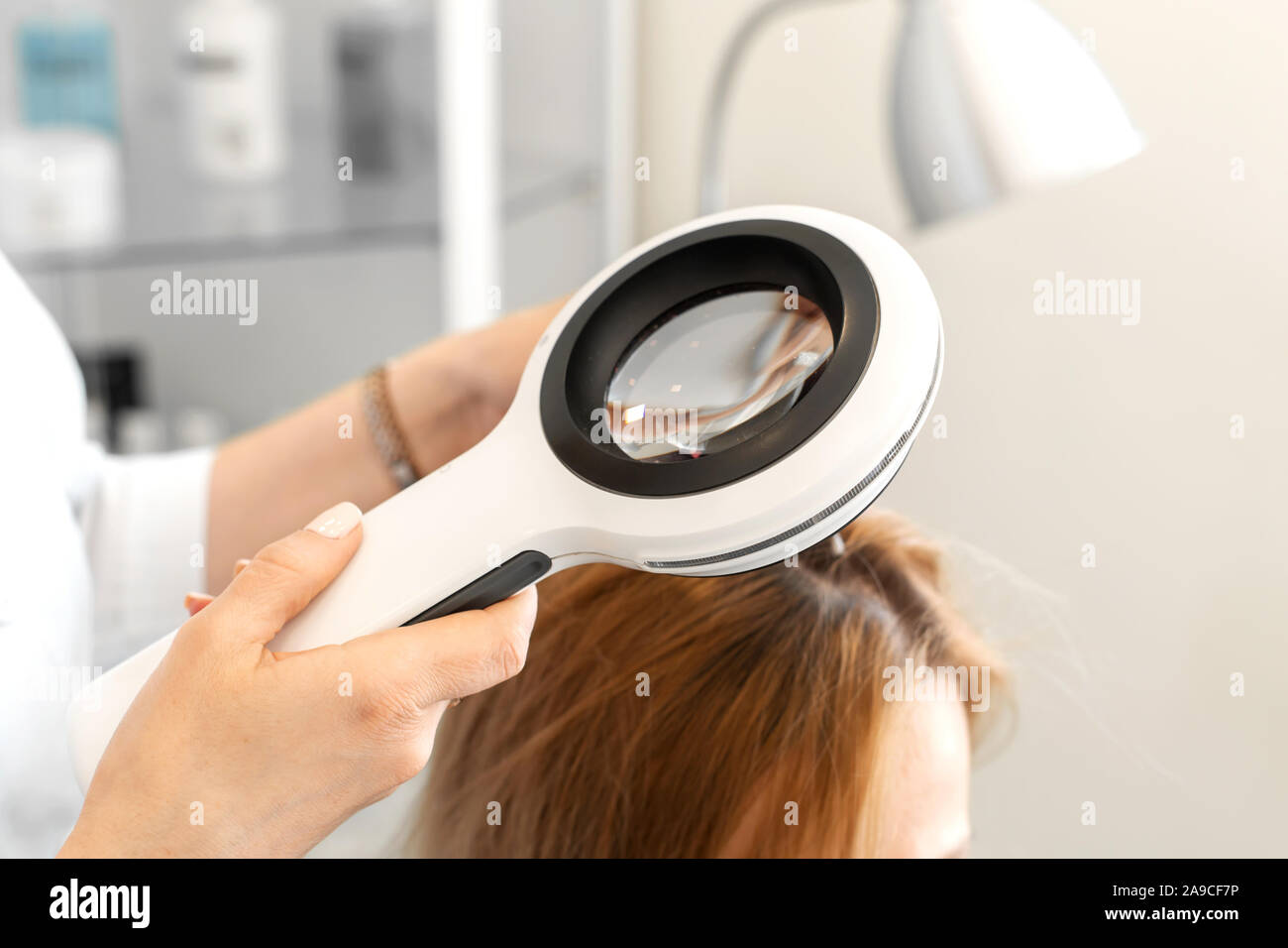 A trichologist examines the condition of the hair on the patient’s head ...