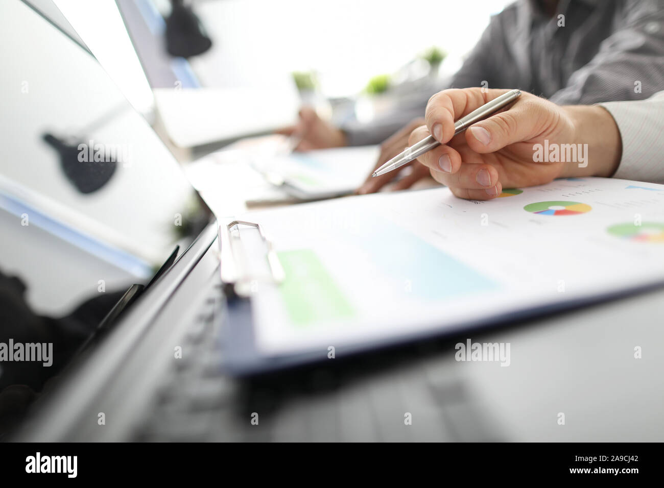 Male clerk making notes with silver pen at annual report Stock Photo ...