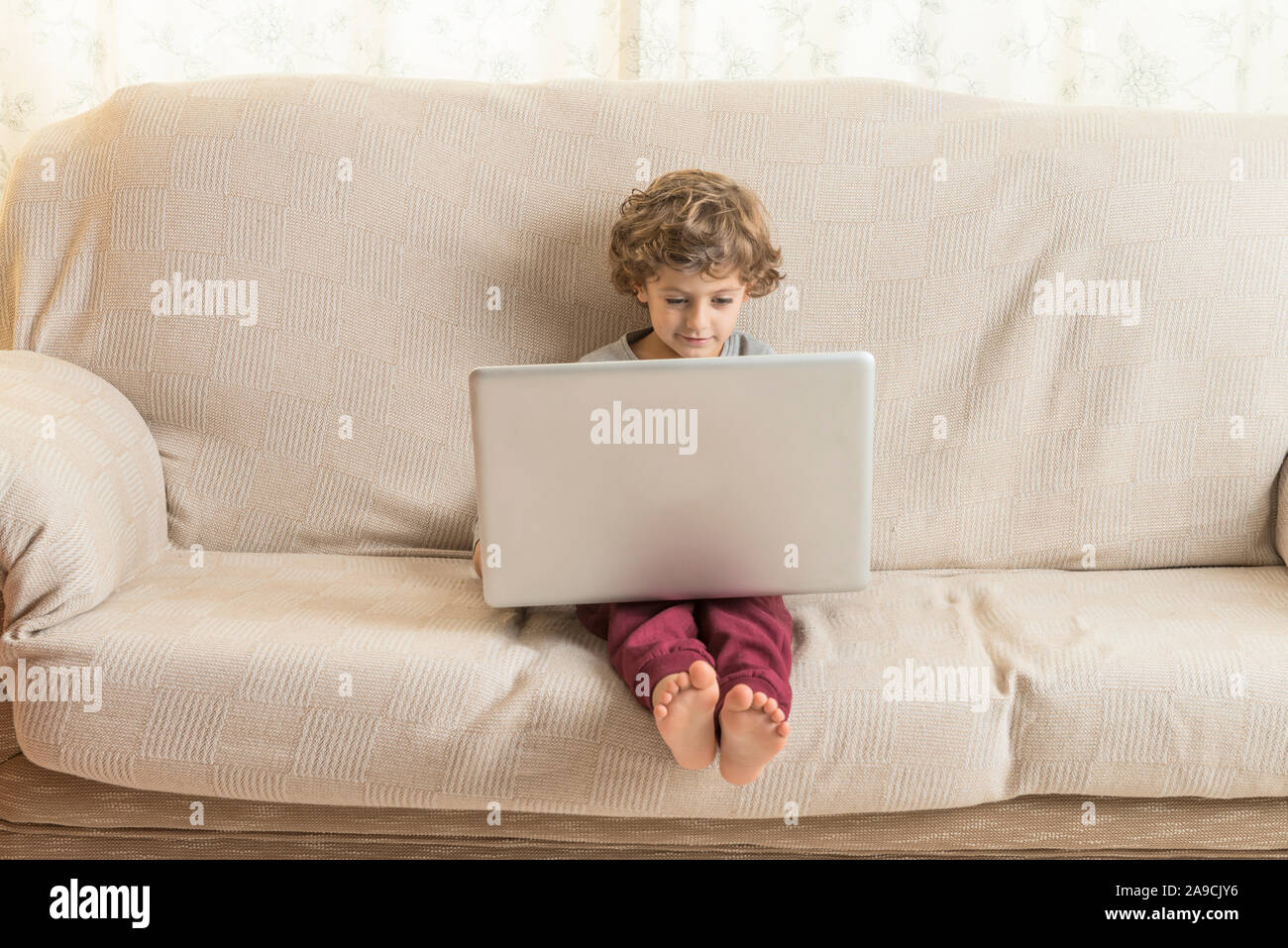 Child sitting on a sofa watching a laptop. Technology concept in ...