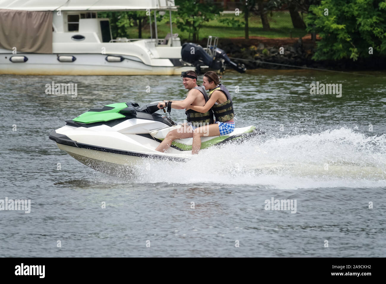 Happy young couple enjoying and having fun riding on a jet ski ...