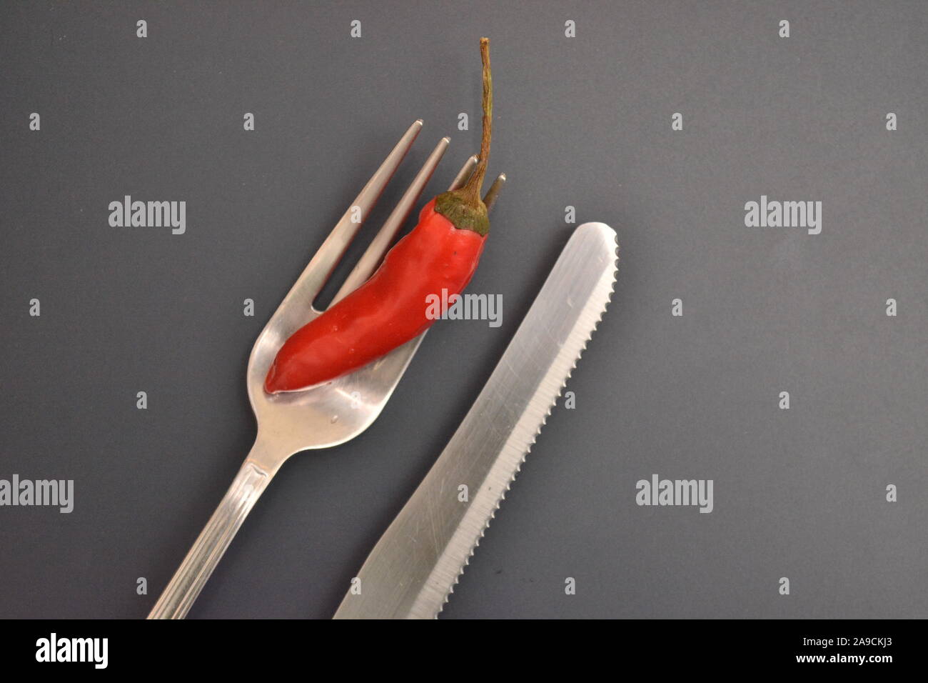 red chili pepper and metal fork and knife Stock Photo - Alamy