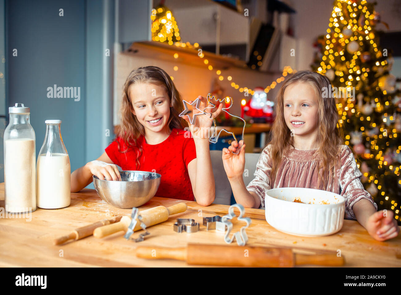 Adorable little girls baking cookies background of lights and Christmas ...