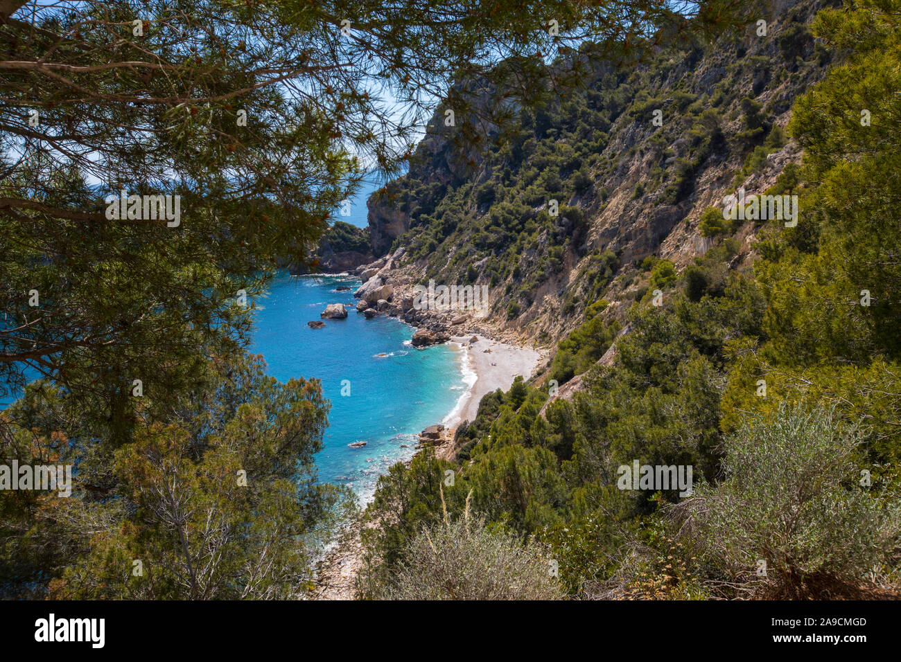 A view through the trees of the stunning Ambolo Beach in Javea, Spain ...