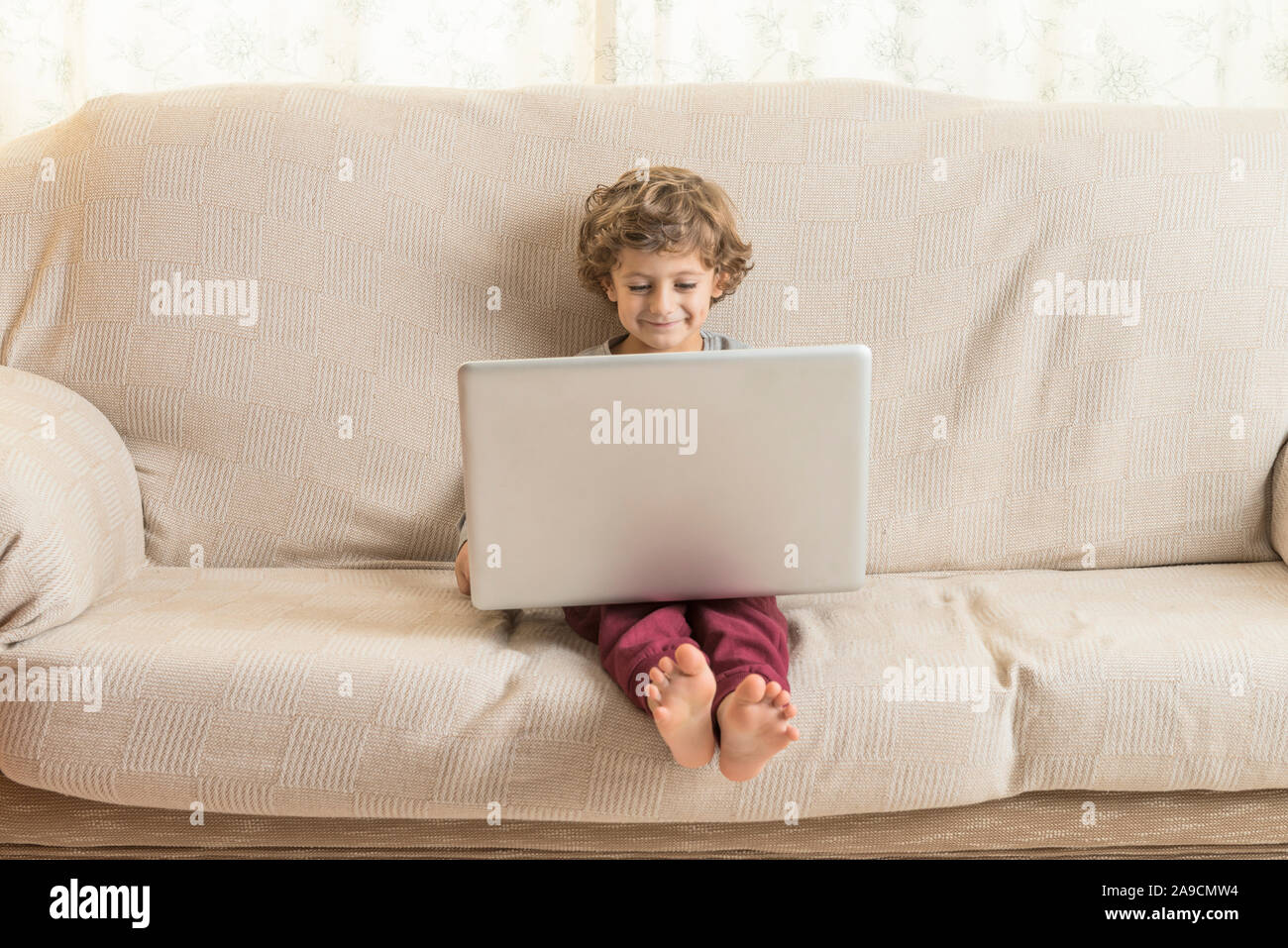 Child sitting on a sofa watching a laptop. Technology concept in ...
