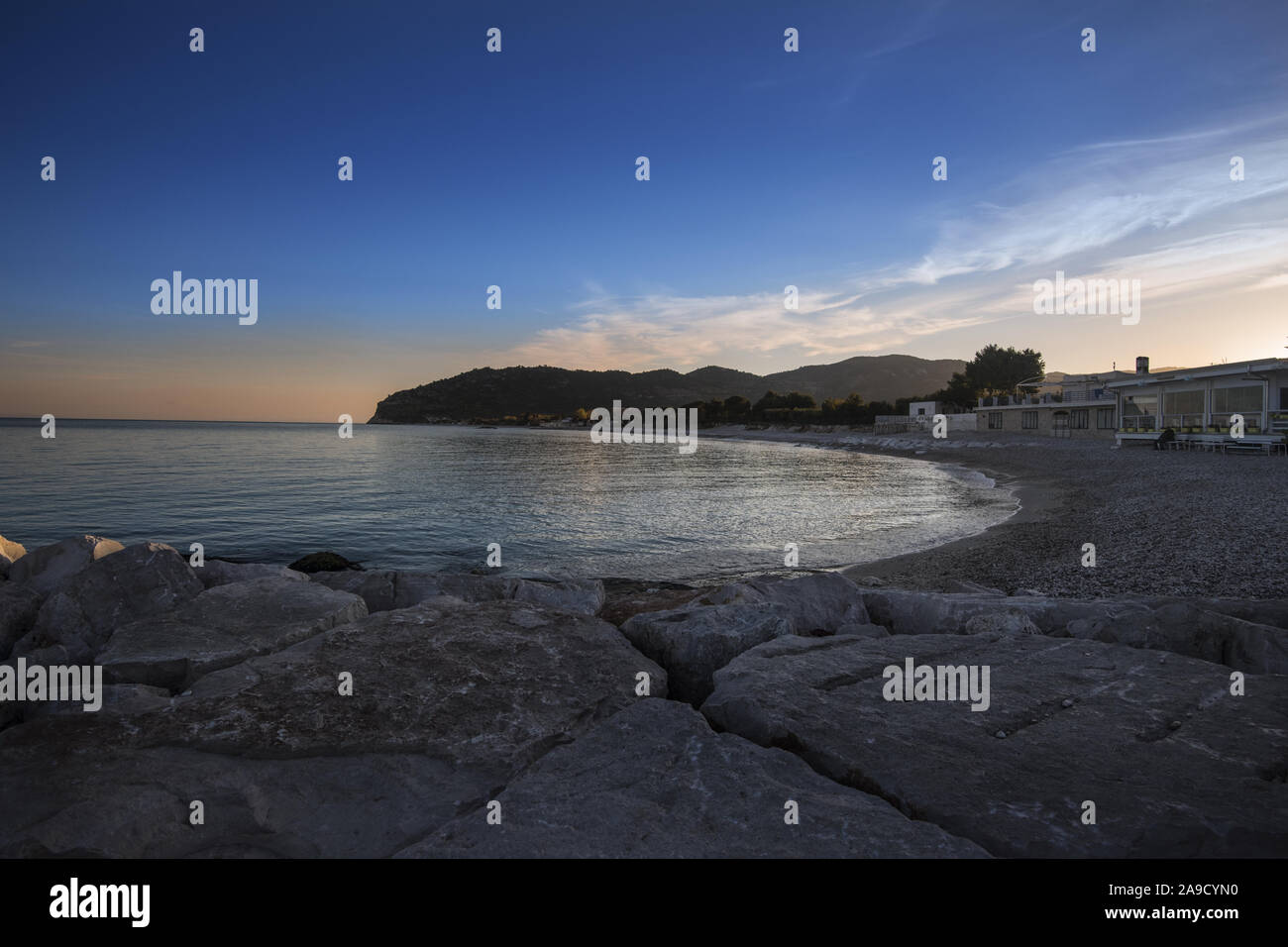 Serene Italian beach with rocks and sunset Stock Photo - Alamy