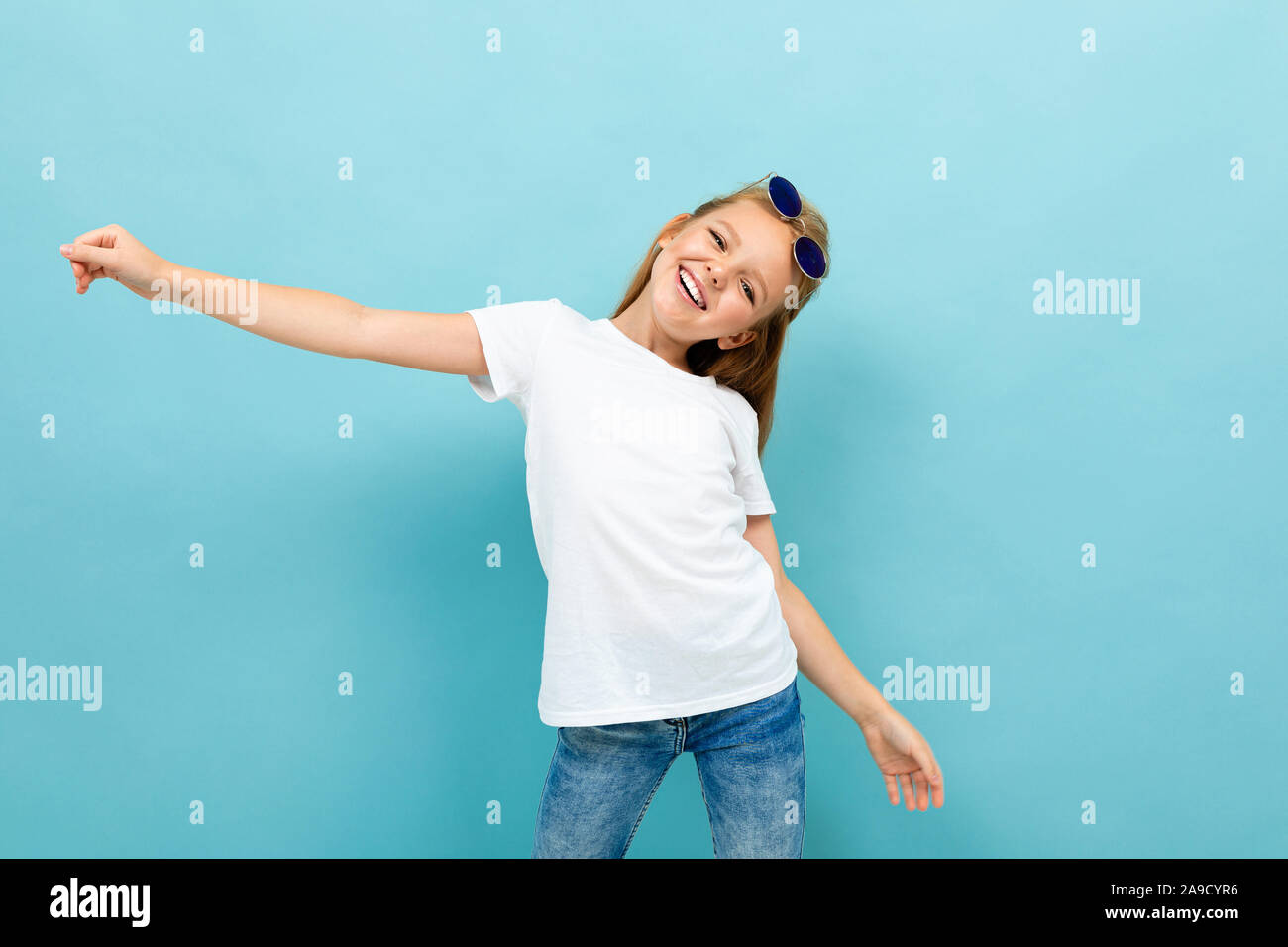contented charismatic girl schoolgirl in a white t-shirt on a blue ...