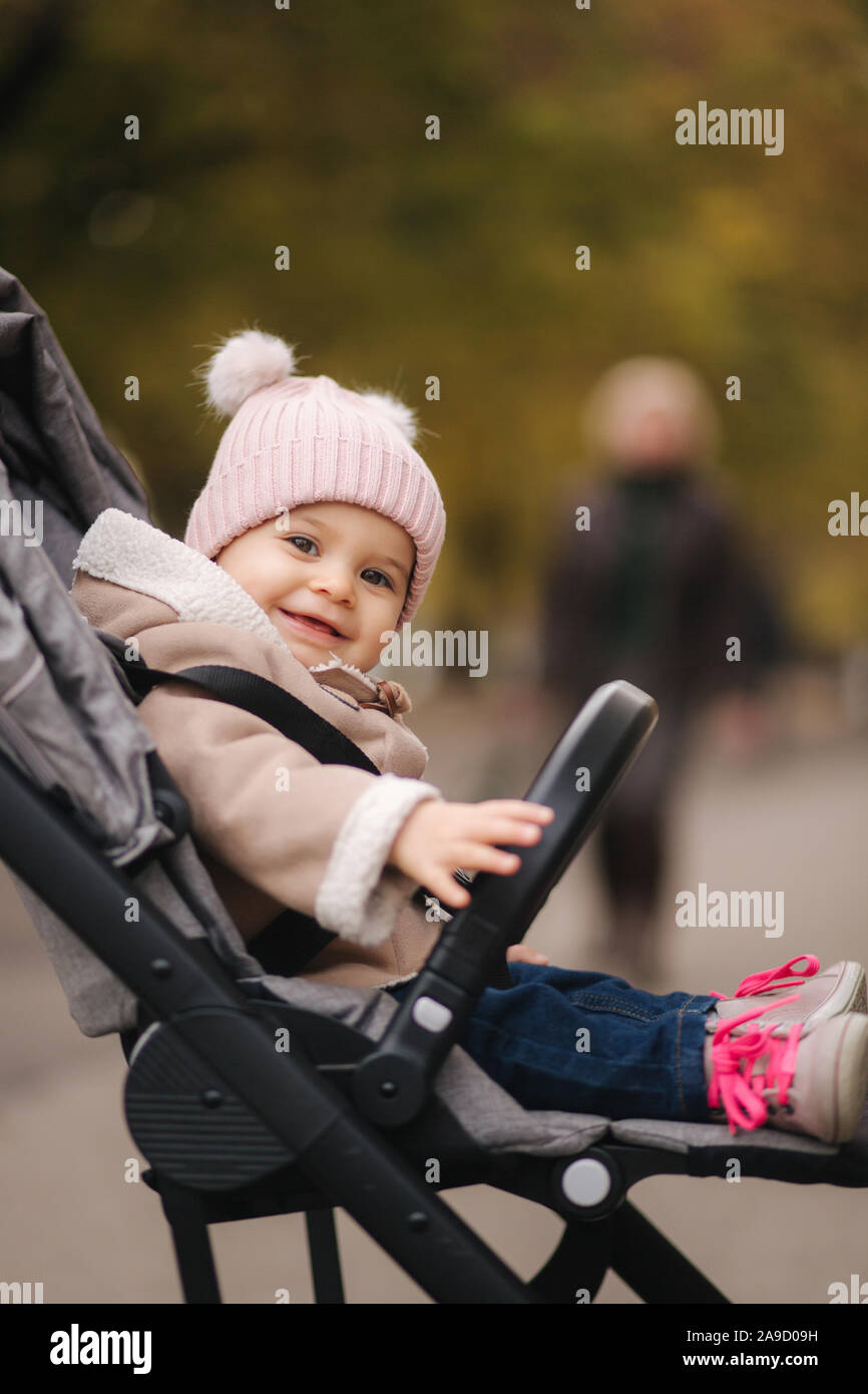 Cute little baby in pram. Adorable baby girl in autumn sitting in her ...