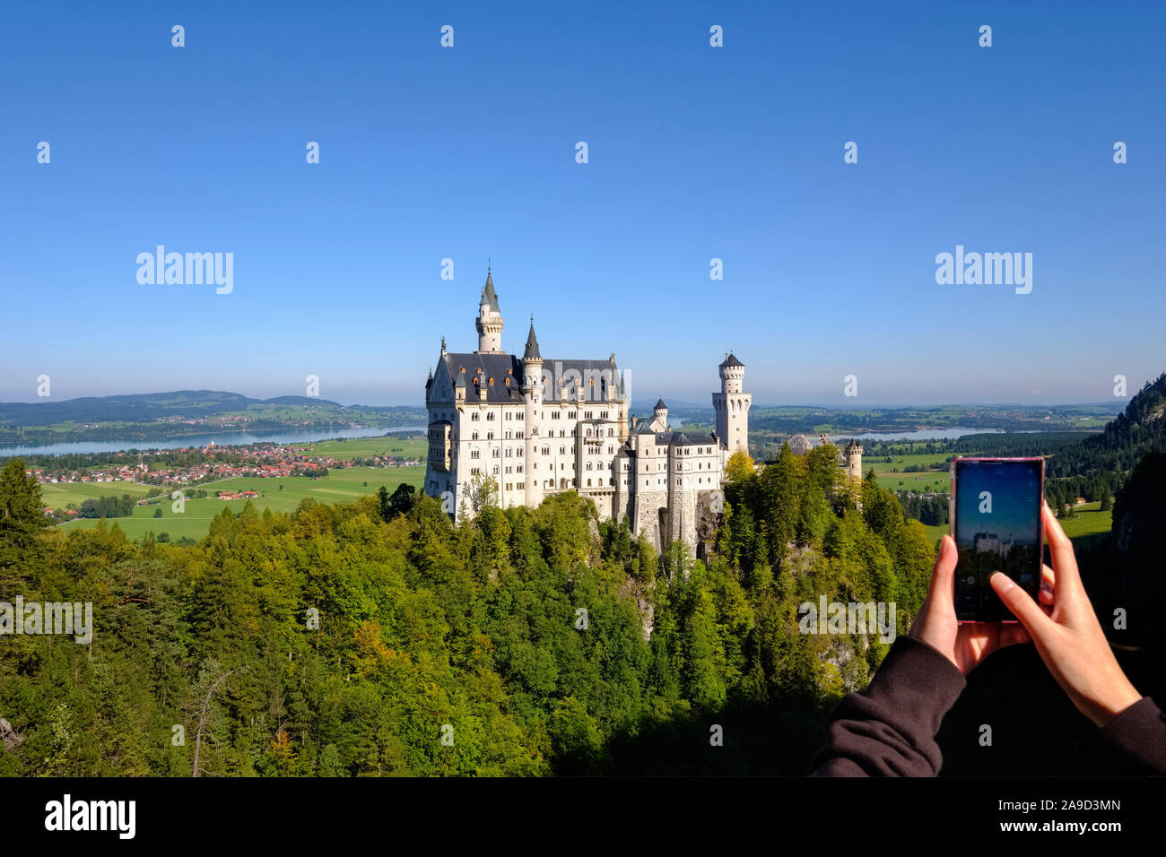 Tourist on Marien bridge takes a photo of Castle Neuschwanstein with ...
