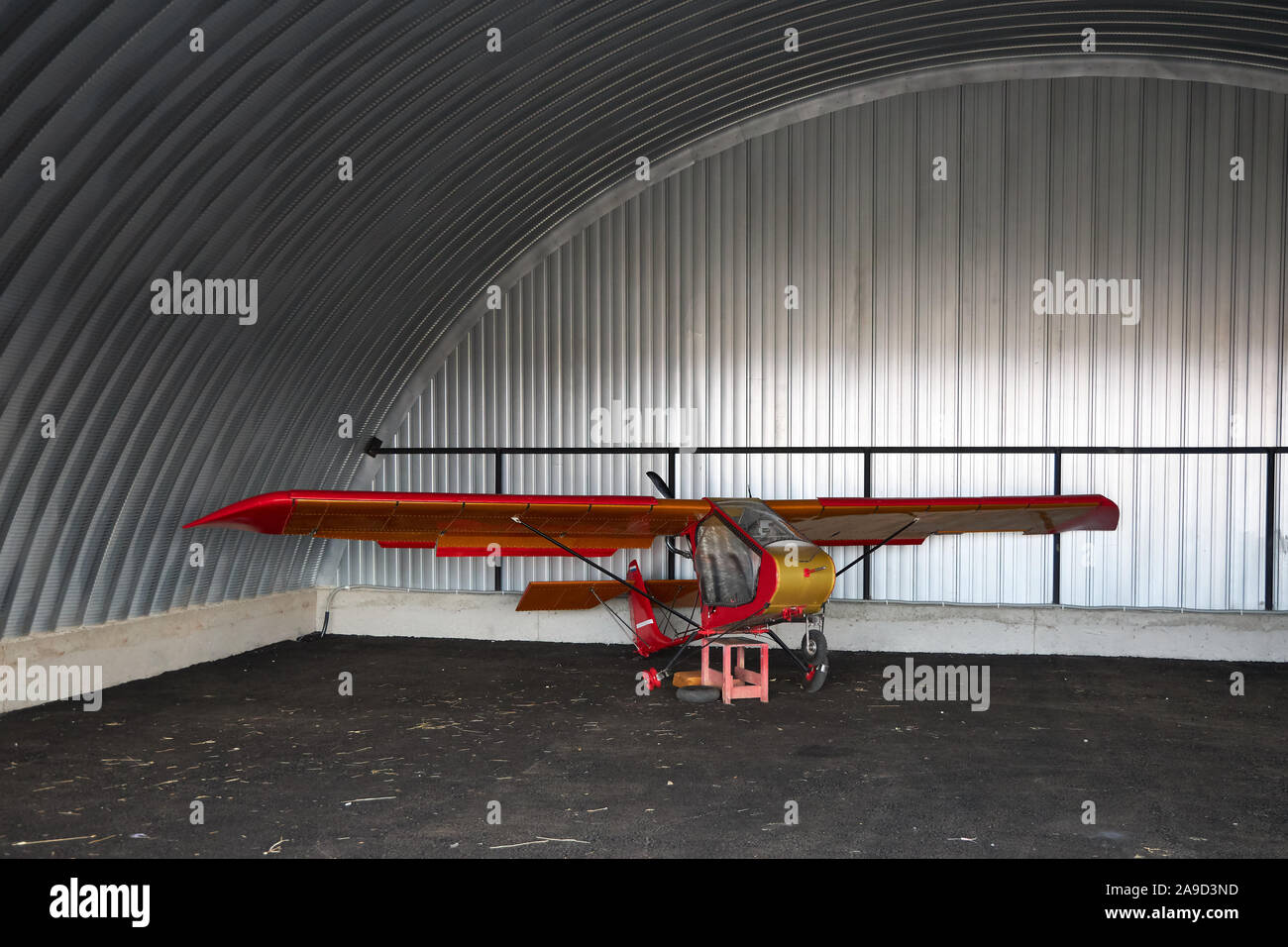 Very small single-place ultralight glider stands in the corner of a ...