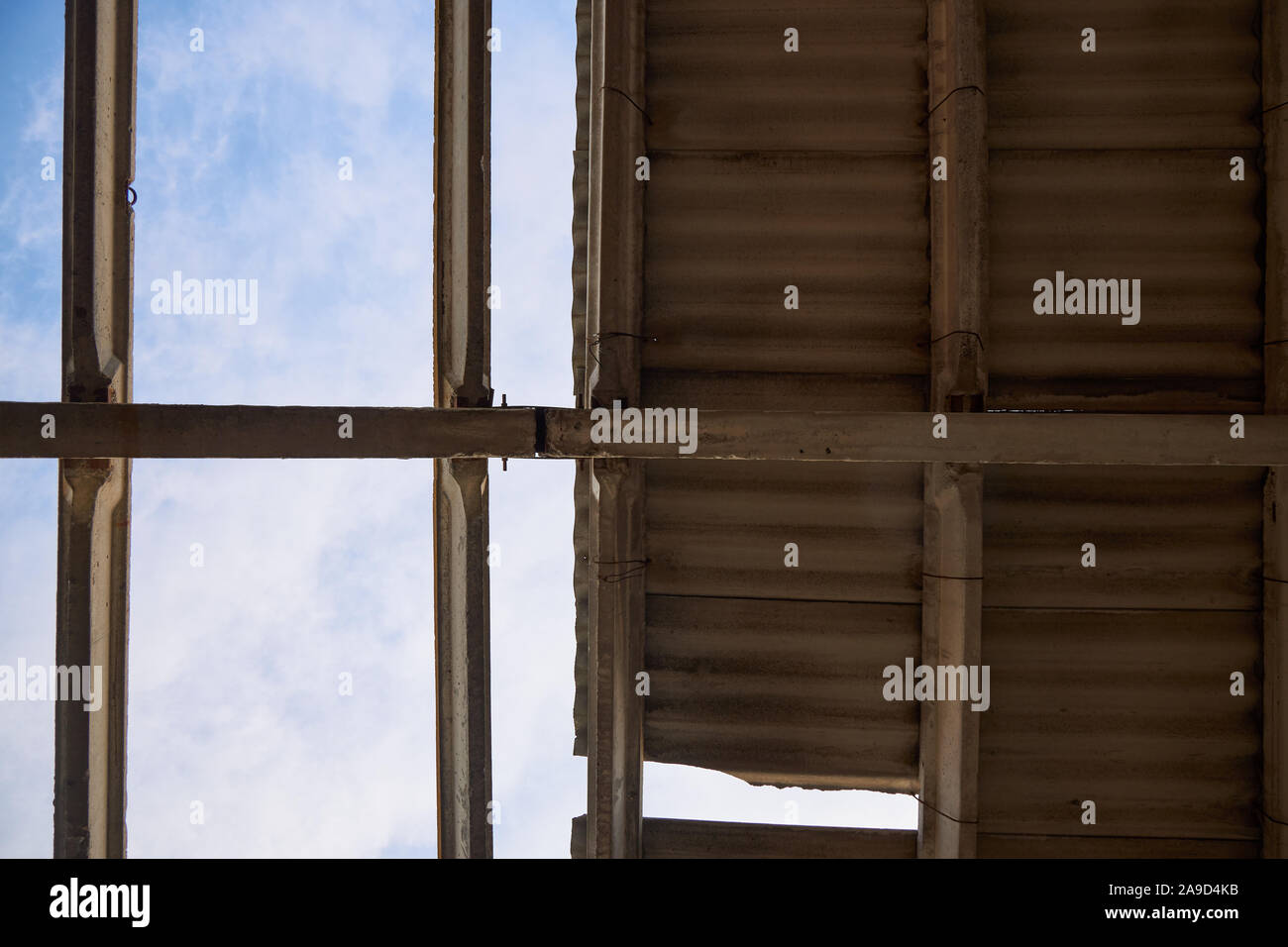 Partially destroyed roof of an old building through which a blue sky is ...