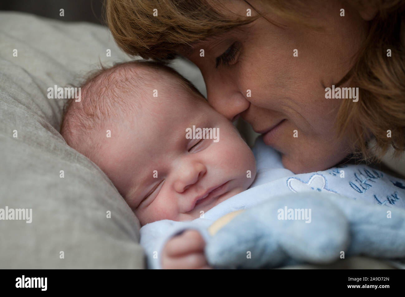 Mother cuddling with sleeping baby, rubbing her nose on baby's cheek ...