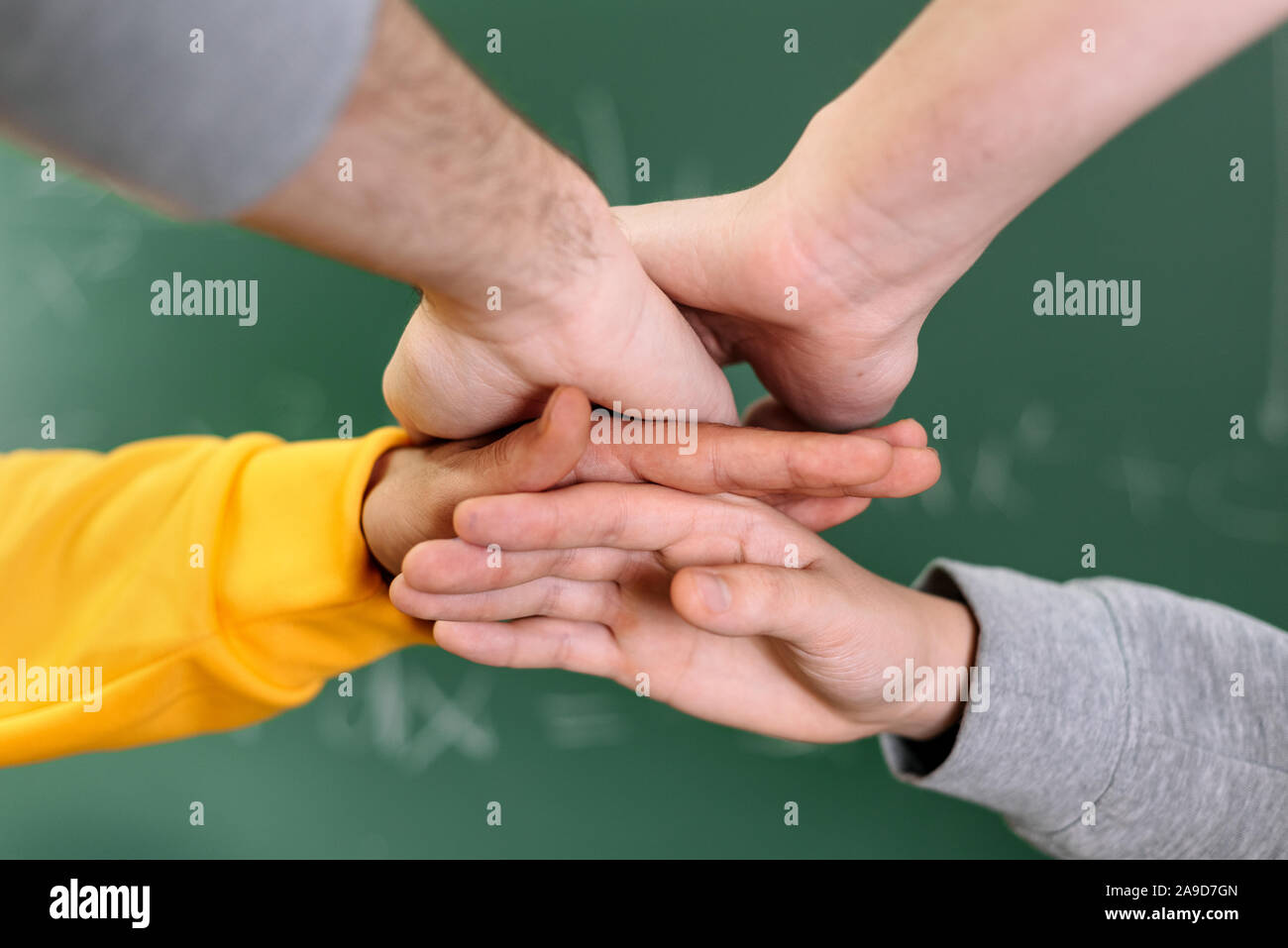 Students putting hands together at the college with a blackboard in the ...