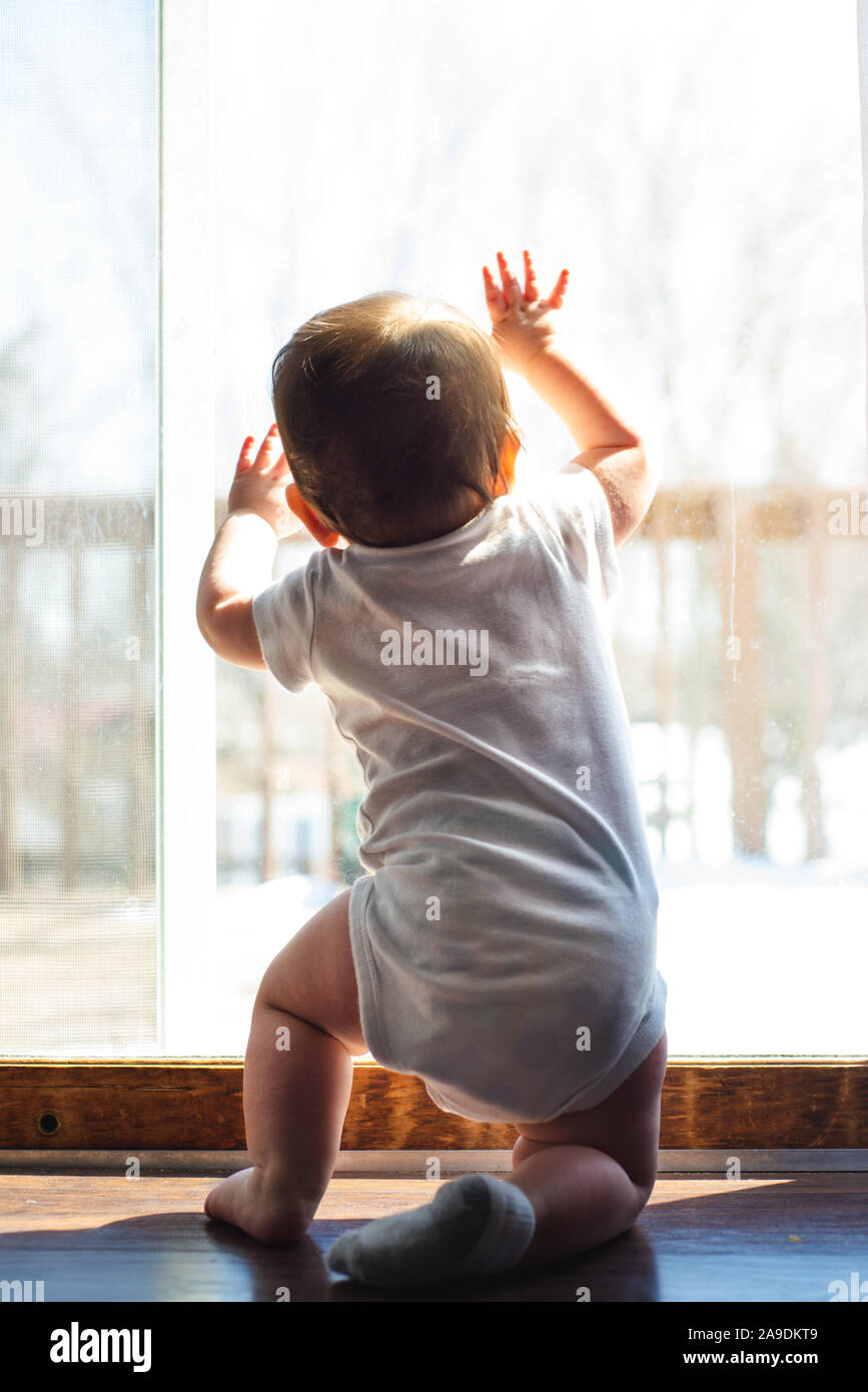 baby crawling up the window to stand Stock Photo - Alamy