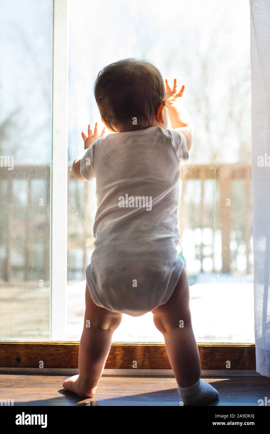 baby crawling up the window to stand Stock Photo - Alamy