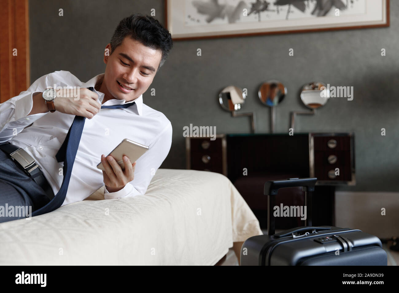 Young man lying in bed watching mobile phone Stock Photo - Alamy