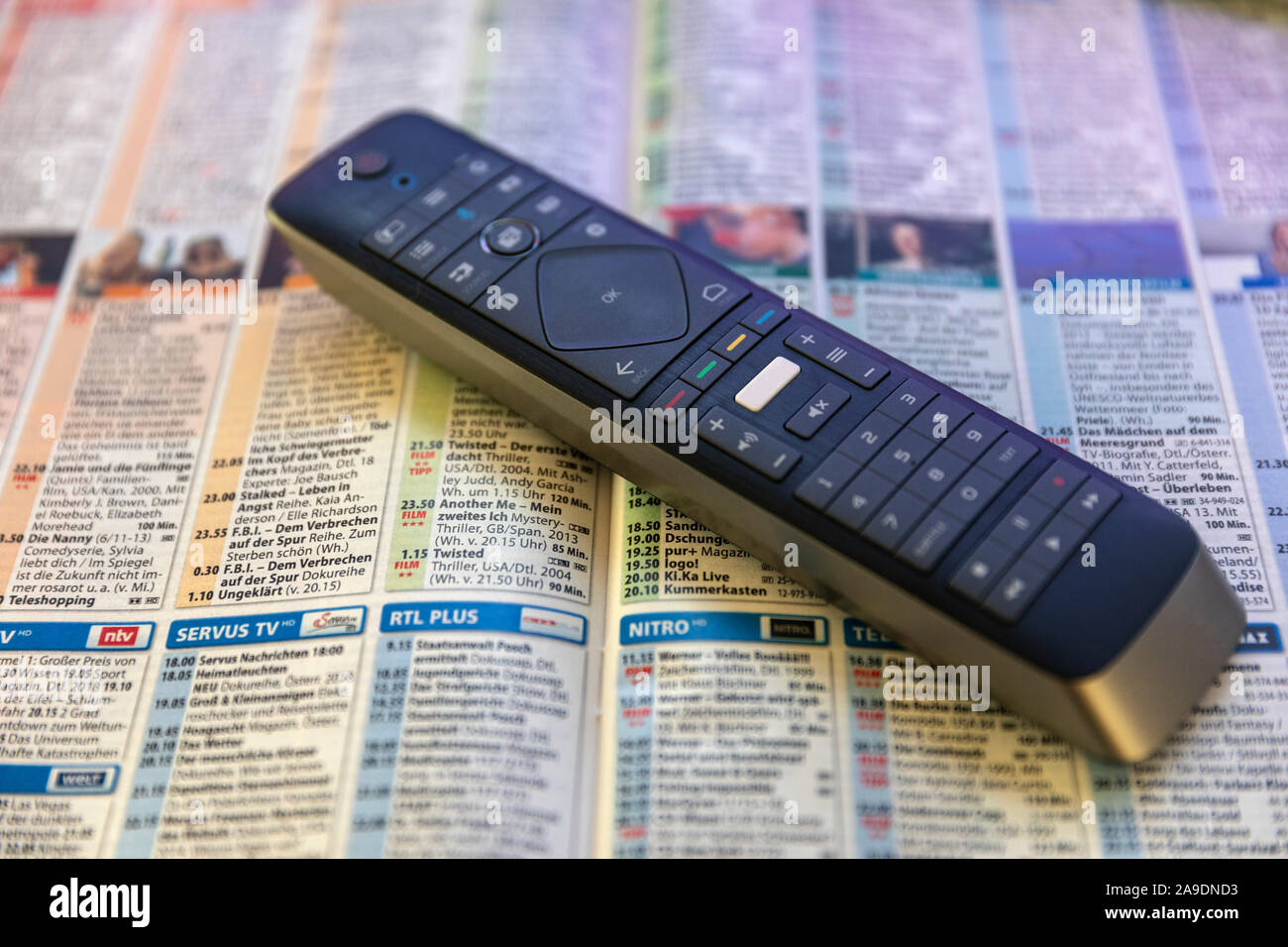 Remote control lying on TV magazine, blur Stock Photo - Alamy