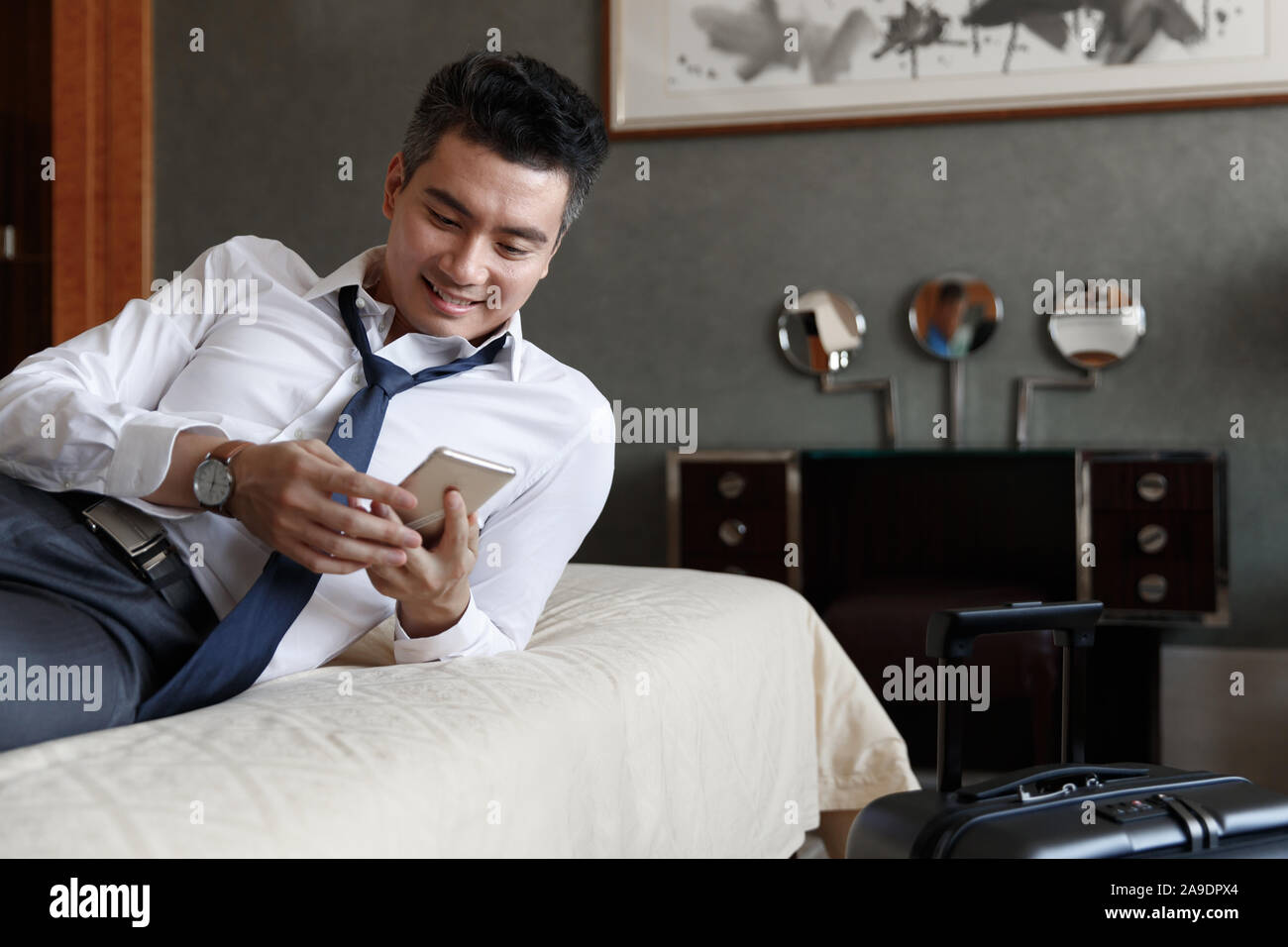 Young man lying in bed watching mobile phone Stock Photo - Alamy