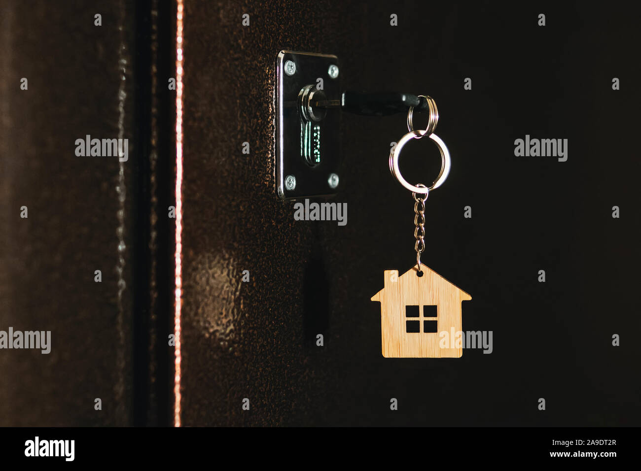 House key with house model keychain in a door. process of opening the ...