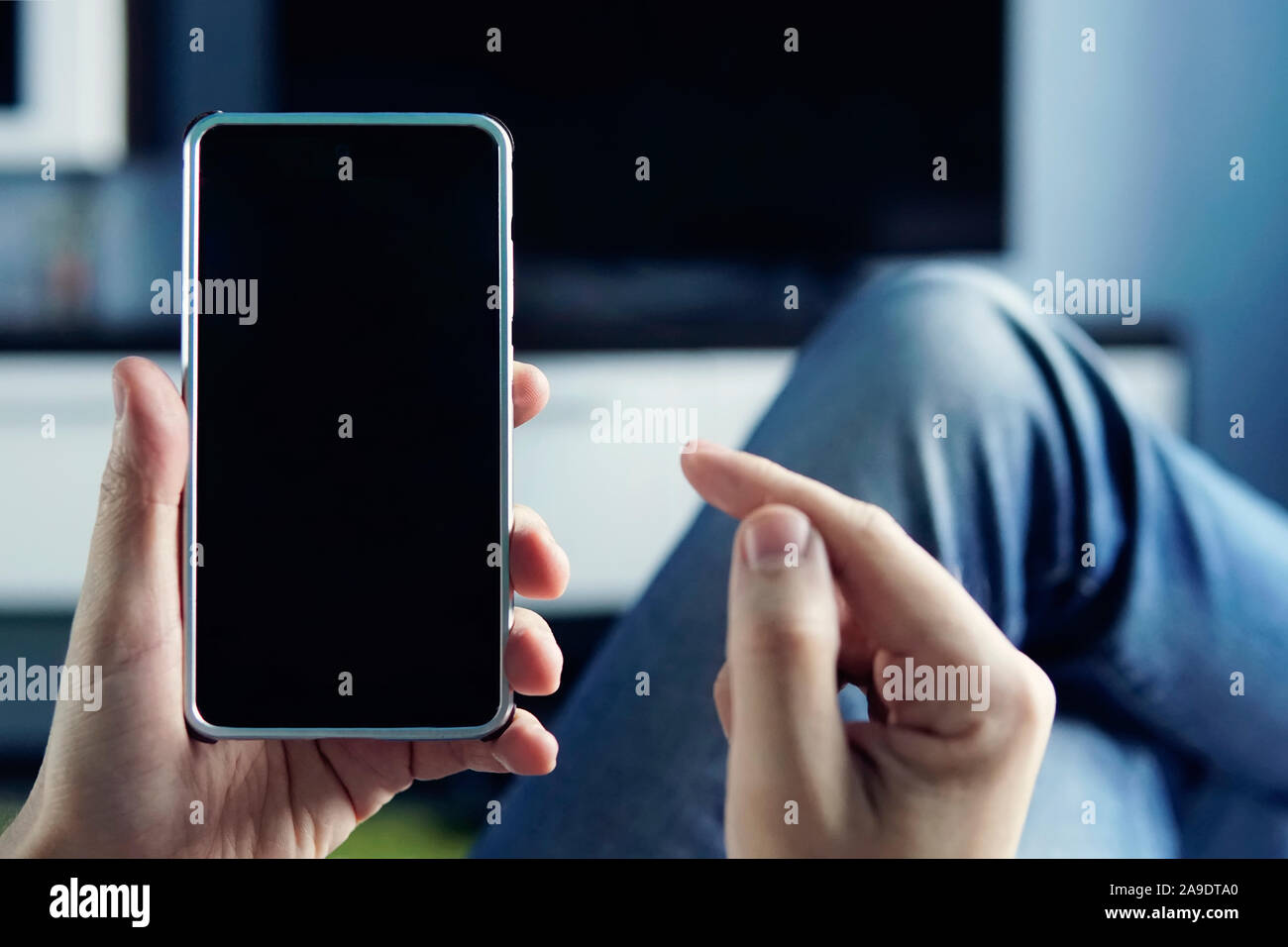 Male hands touching smartphone screen on dark flat with copy space ...
