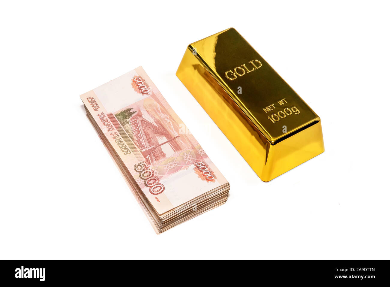 A gold bar and a wad of 5000 banknotes are isolated on a white ...