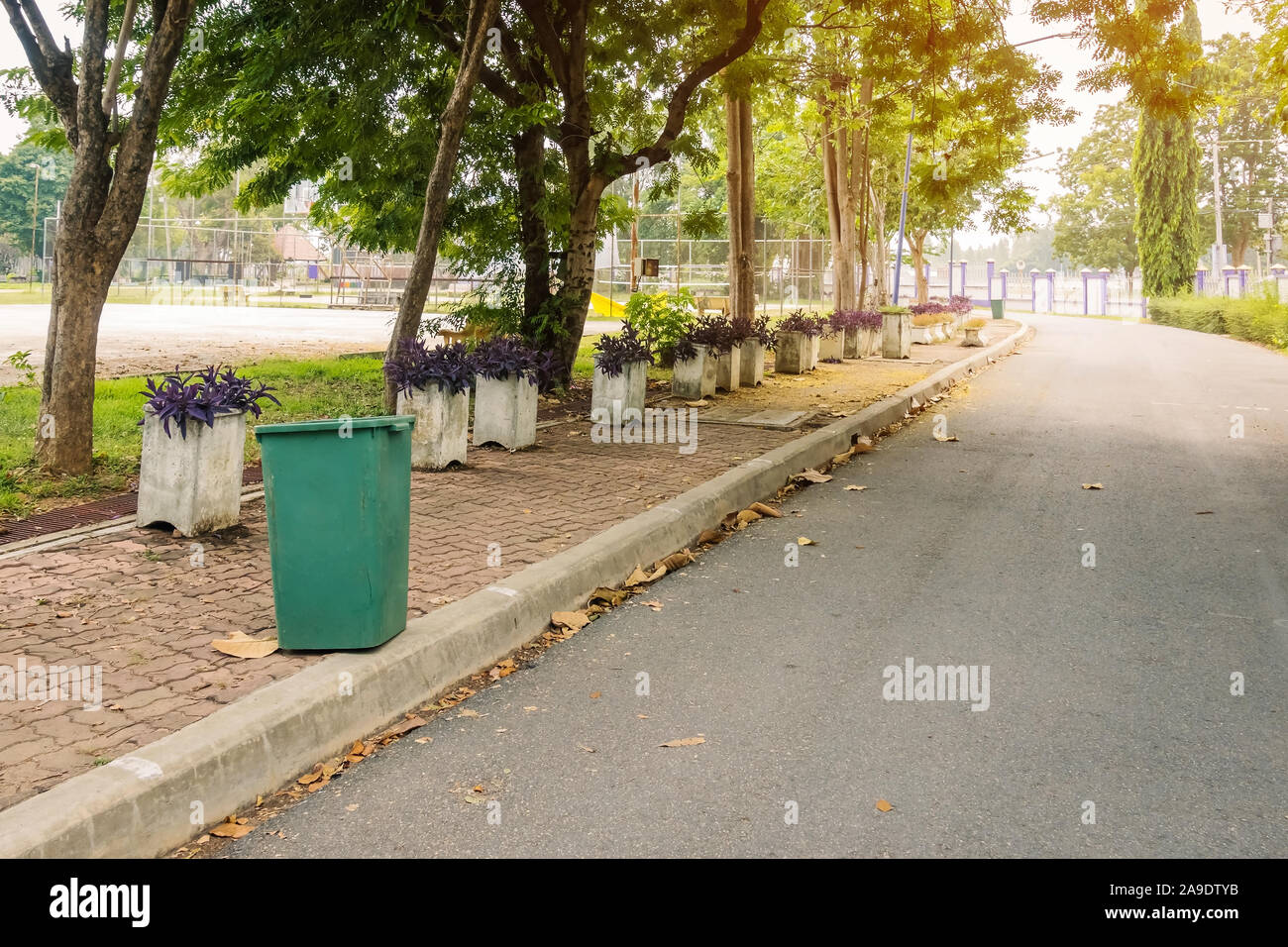 An old green dustbin in the public park beside the walk way for protect ...