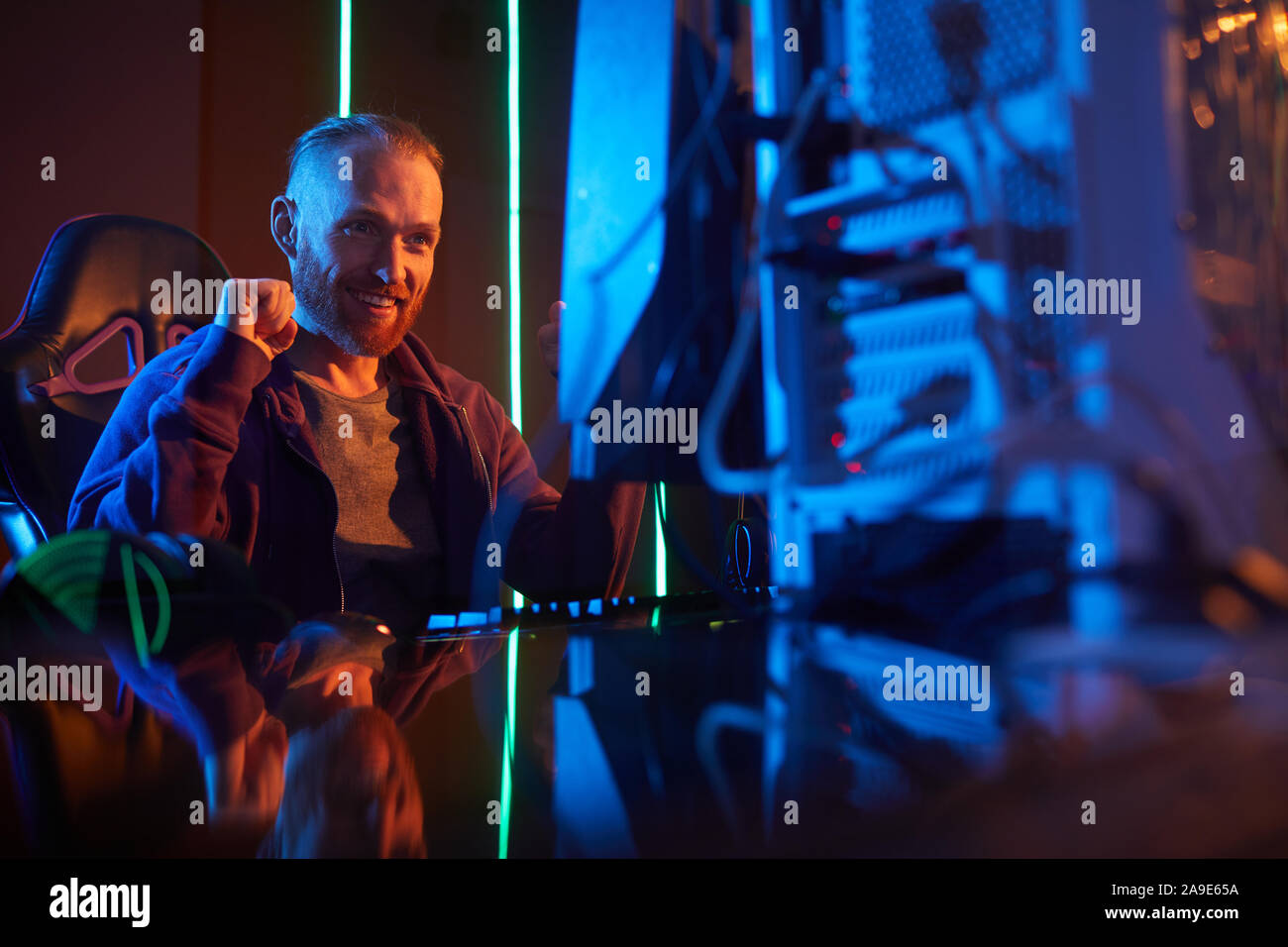 Young bearded man sitting in front of computer monitor gesturing and ...