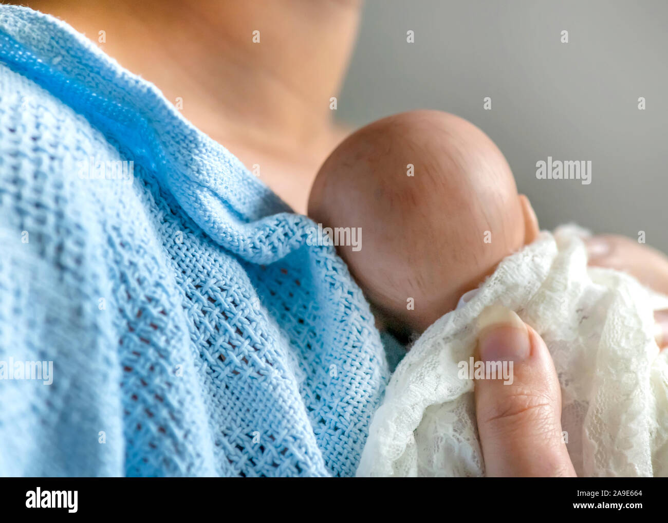 premature newborn baby wrapped in lace blanket , mother holding her ...