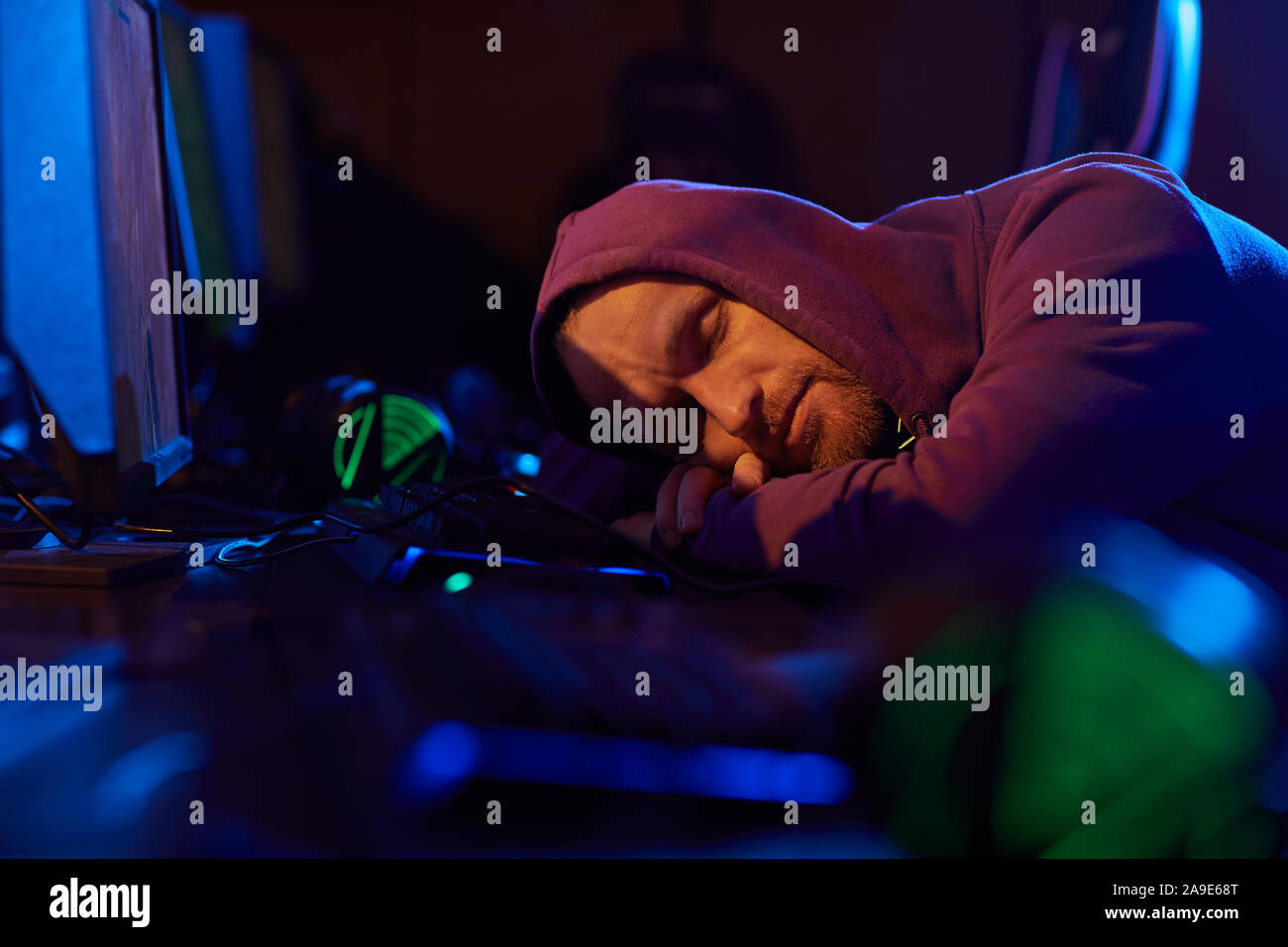 Young computer programmer lying on the desk in front of computer ...