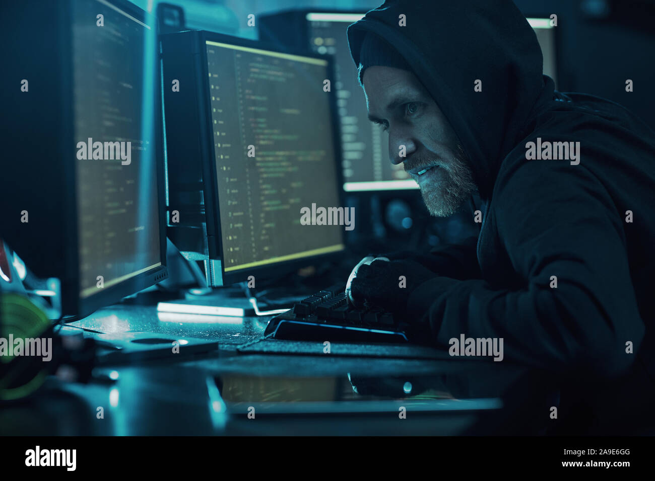 Bearded Young Computer Hacker Sitting At The Table And Typing On Computer Keyboard He Breaking