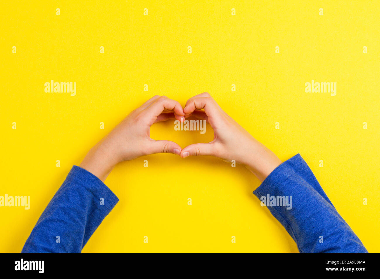 Kid hands making a heart shape on yellow background. Top view Stock ...