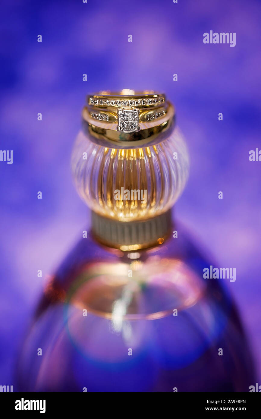 Wedding rings on the lid of a perfume bottle against a purple ...