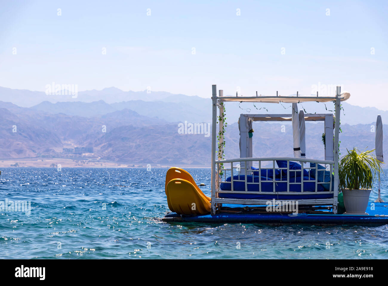 A pier floating on the water with sunbeds for relaxation and surfboards ...